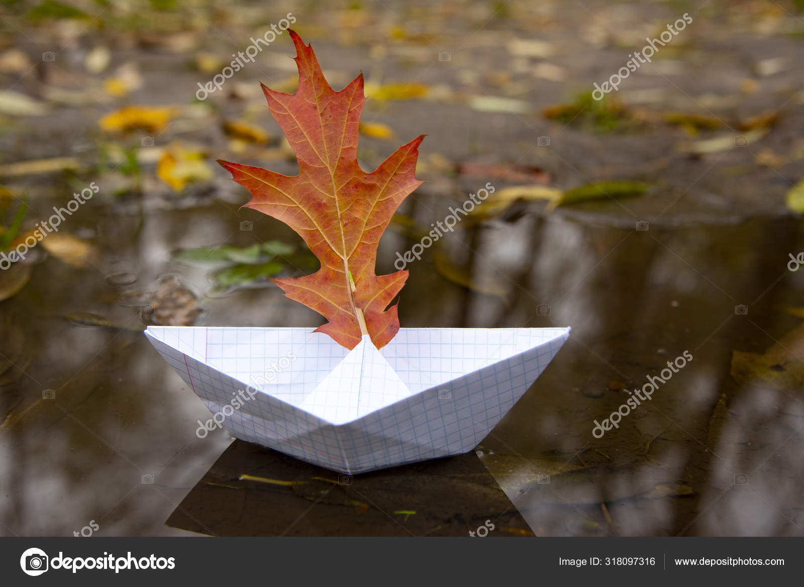 A ship made of notebook paper with a red oak leaf instead of a sail is ...