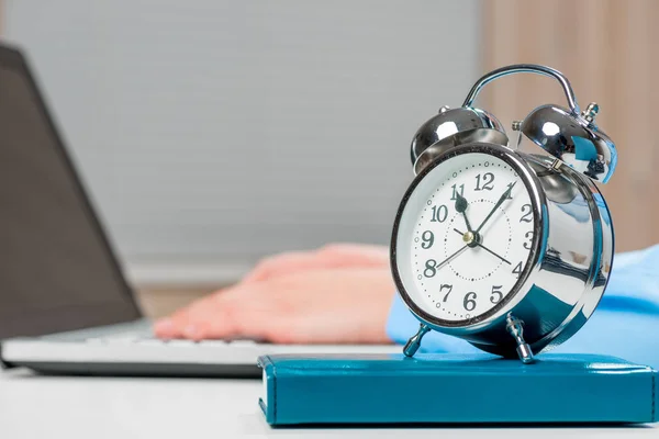Alarm clock on desk in office close-up and secretary's hands out ...