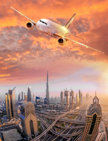 Airplane is flying over Dubai against colorful sunset in United Arab ...