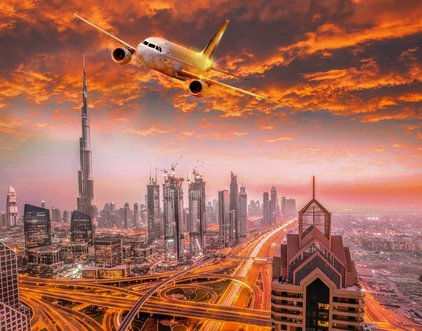 Airplane is flying over Dubai against colorful sunset in United Arab ...