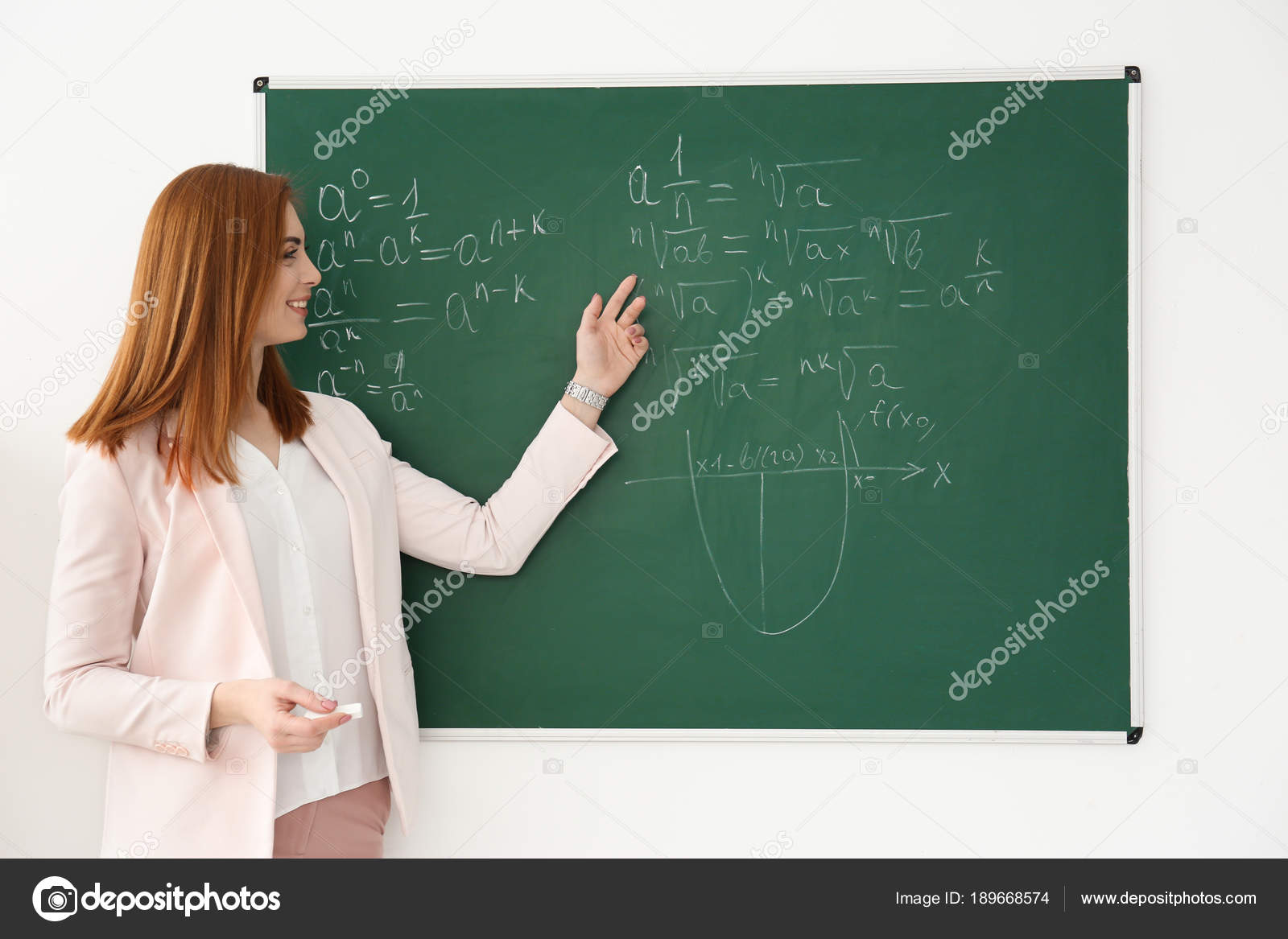 Hermosa maestra joven explicando fórmulas matemáticas escritas en ...