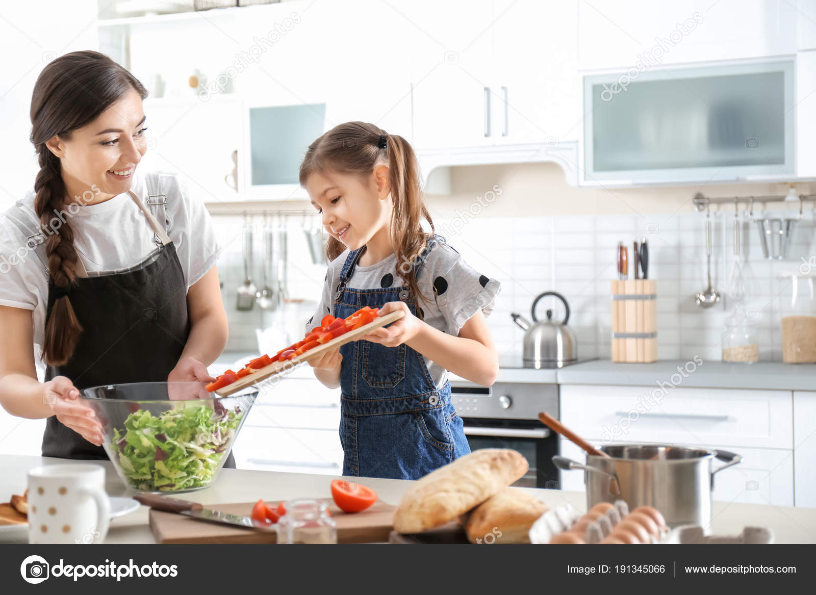 Young nanny with cute little girl cooking together in kitchen Stock ...
