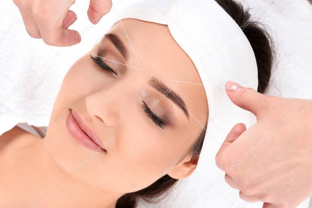 Mujer joven que tiene procedimiento profesional de corrección de cejas ...