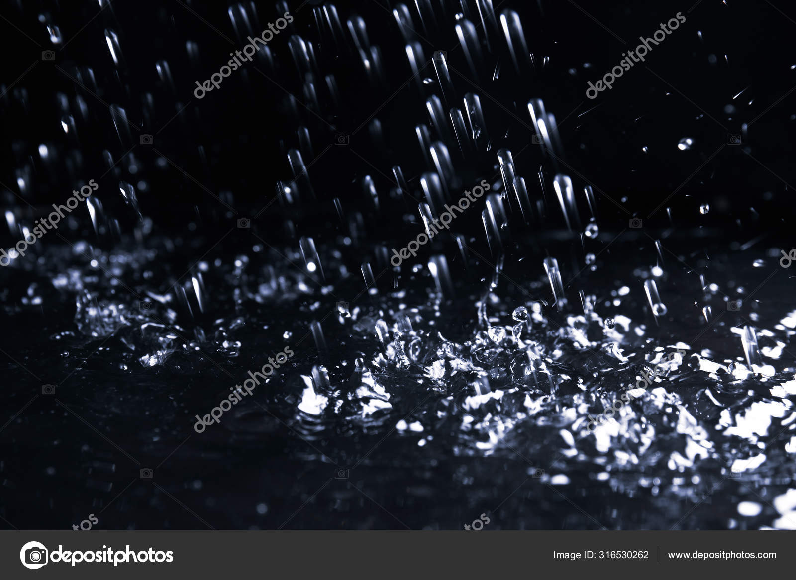 Heavy rain falling down on ground against dark background, closeup ...