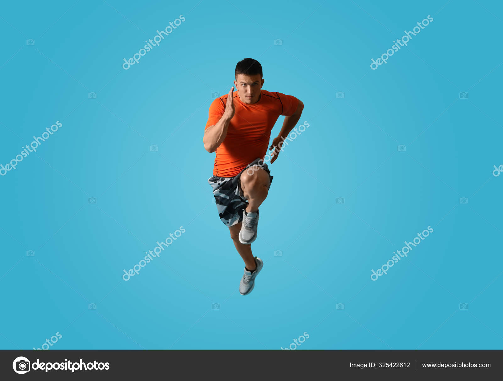 Athletic young man running on light blue background — Stock Photo ...