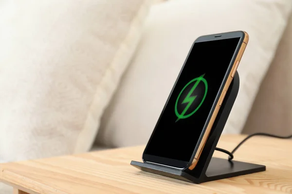Modern mobile phone charging on wireless pad in bedroom, closeup. Space ...