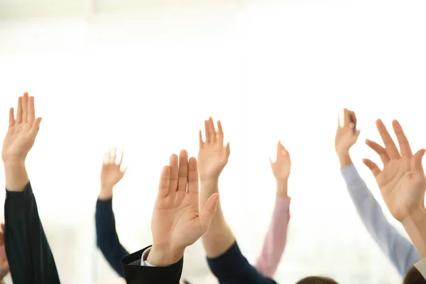 People raising hands to ask questions at business training on light background, closeup - Stock ...