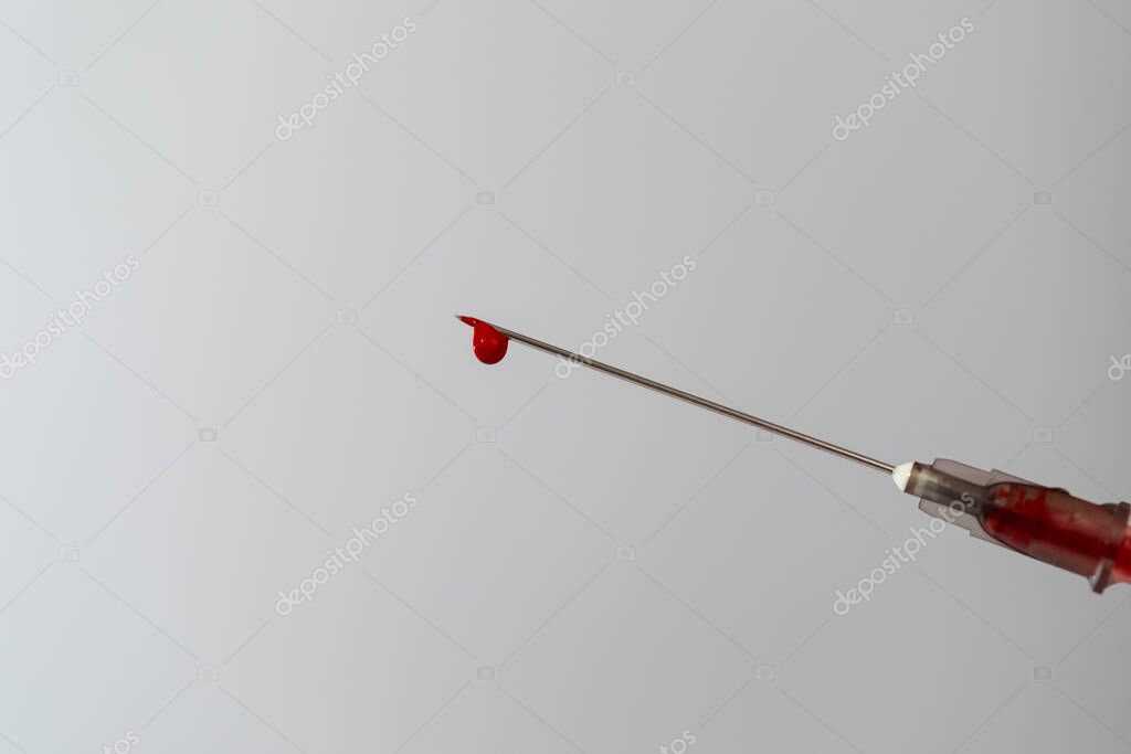 Jeringa con una muestra de sangre. Una gota de sangre al final de la ...