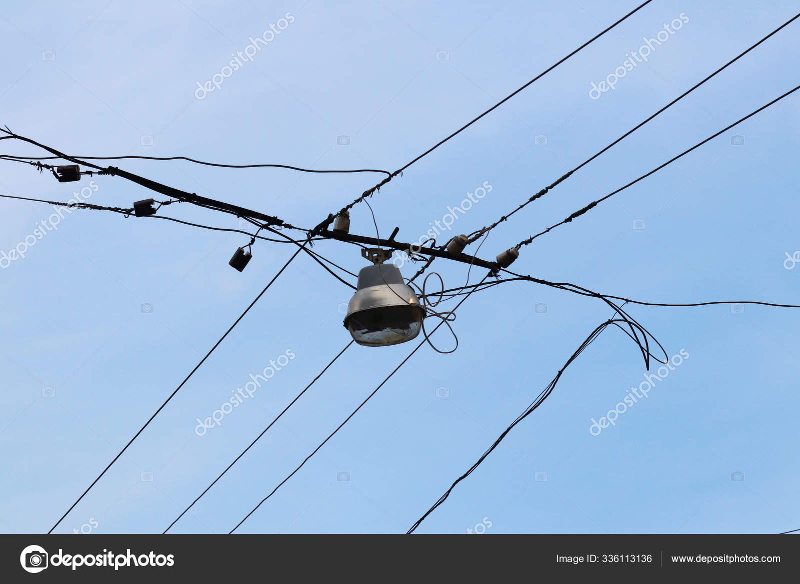 A high-voltage power line illuminated by sunlight against a background ...