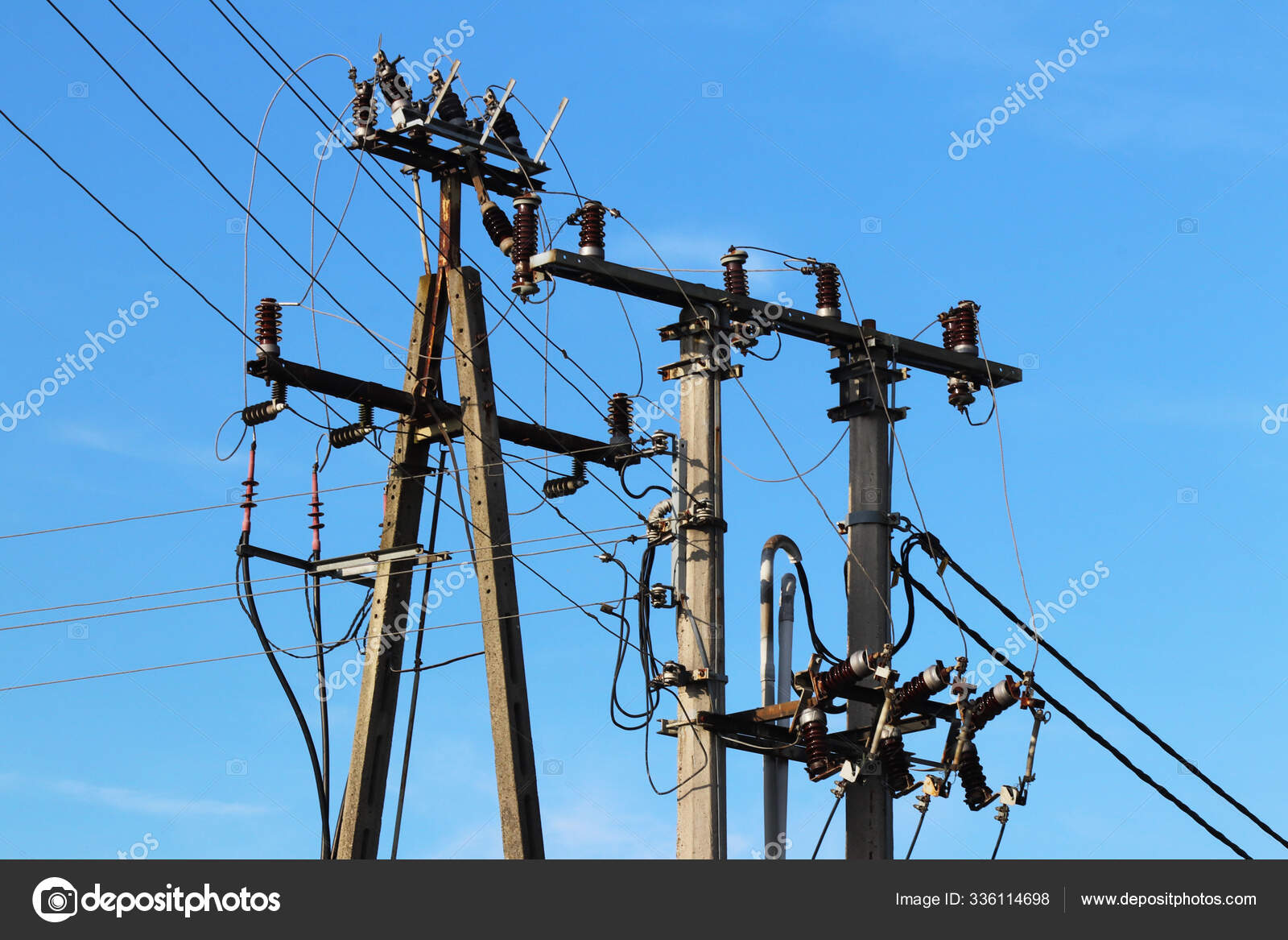 A high-voltage power line illuminated by sunlight against a background ...