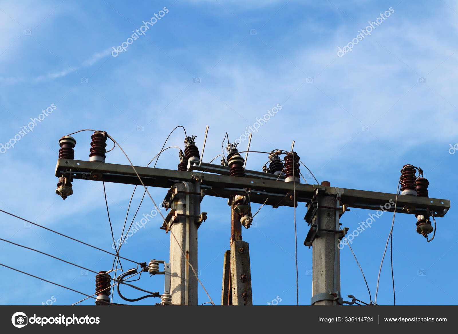 A high-voltage power line illuminated by sunlight against a background ...