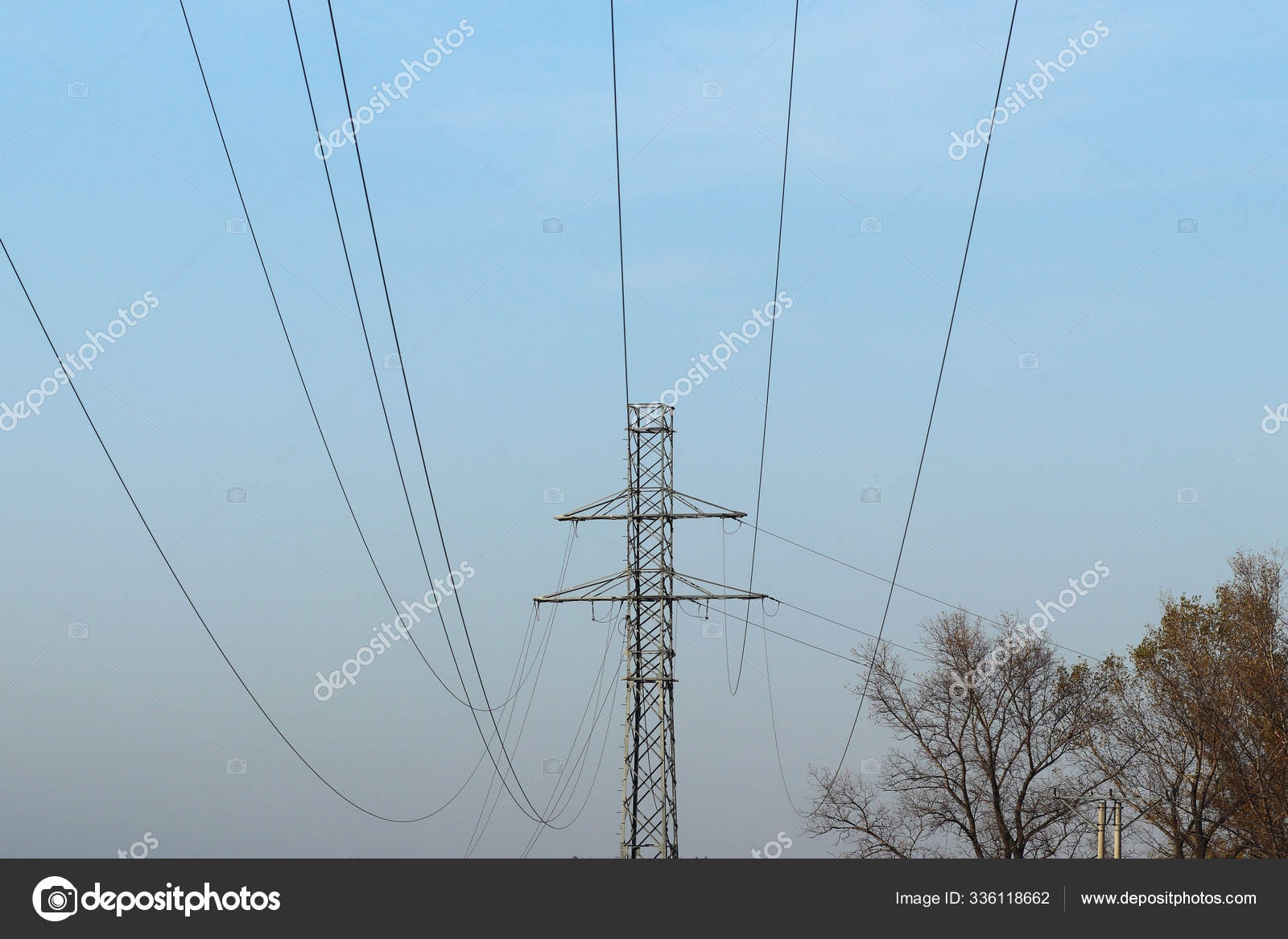 A high-voltage power line illuminated by sunlight against a background ...