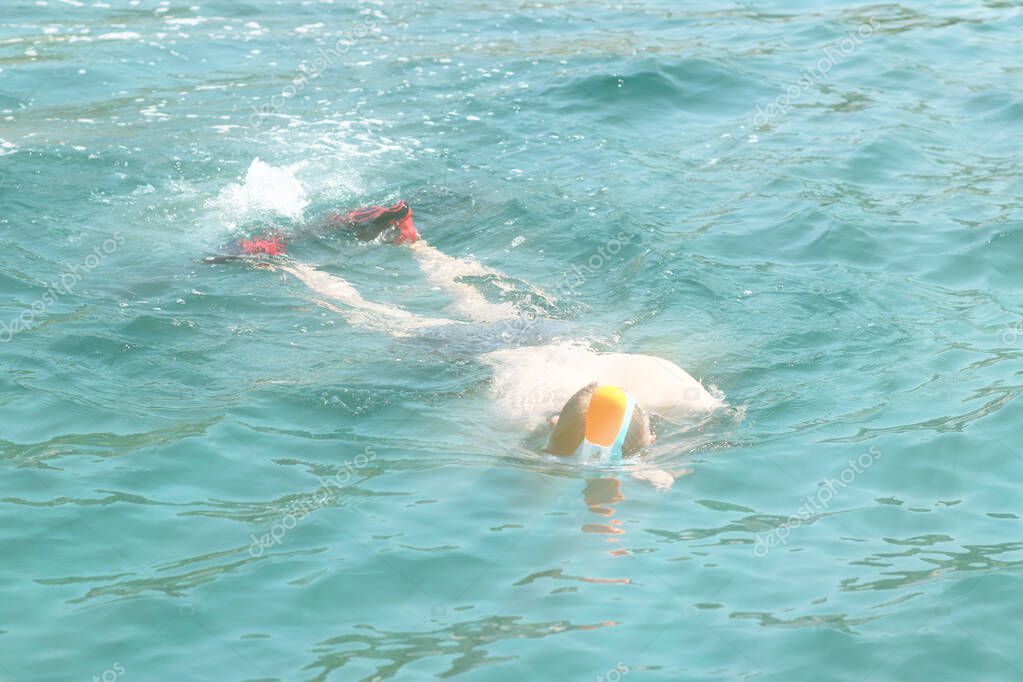 Un niño con una máscara de buceo nada en el mar despejado ...