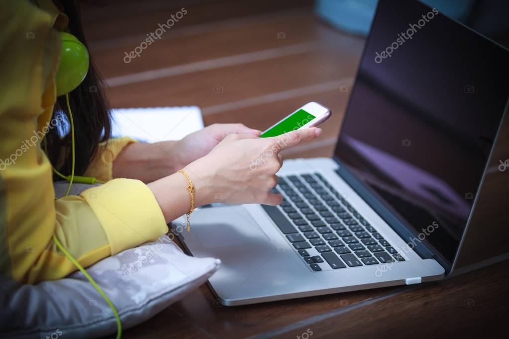 Las manos de la mujer usando el teléfono celular y el ordenador ...