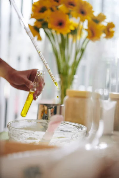 Close-up image of woman using long glass pipette when adding some drops ...