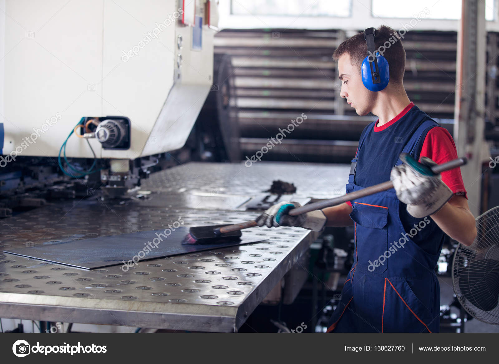 Inside a factory, industrial worker in action on metal press machine ...