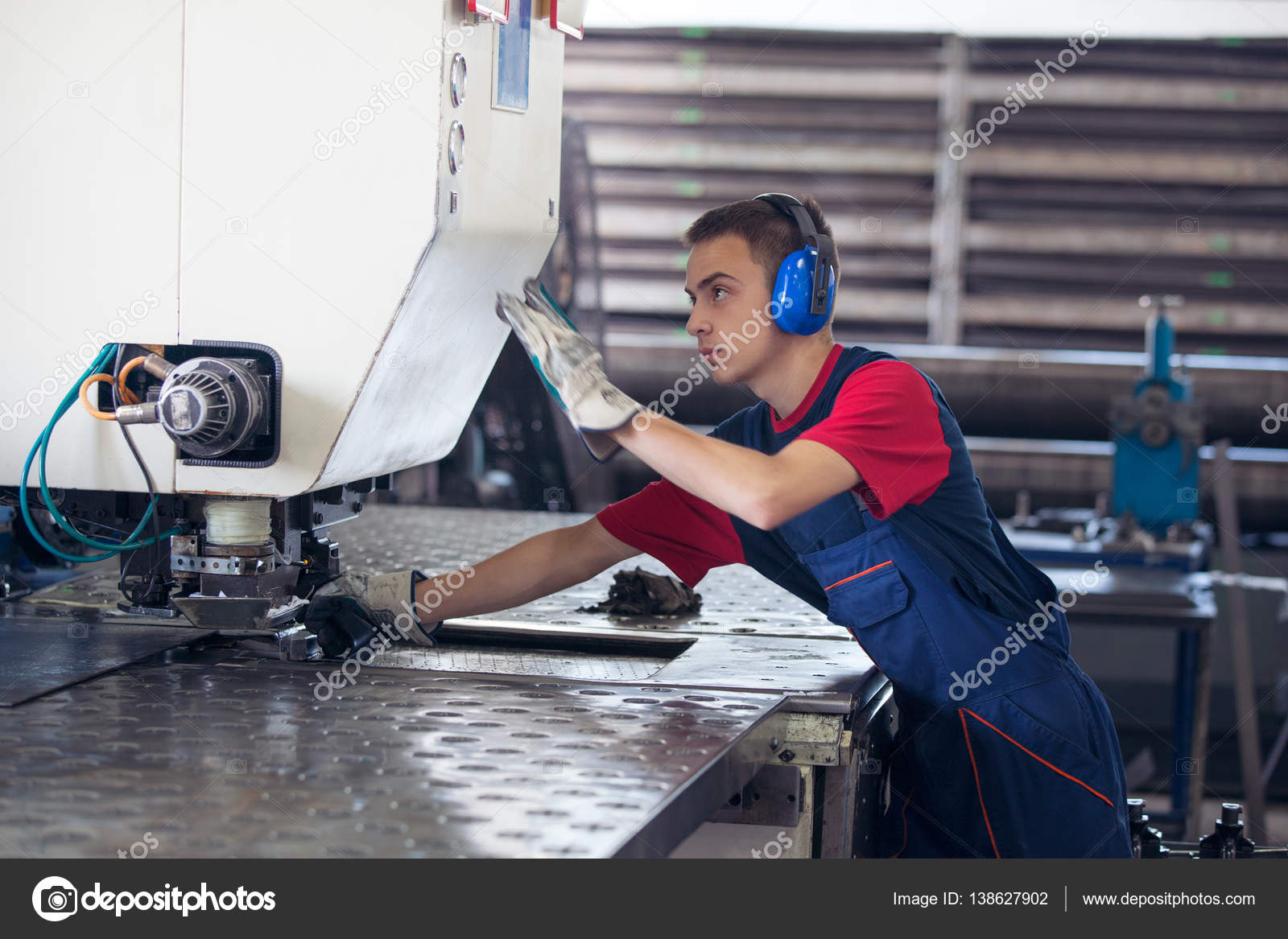 Inside a factory, industrial worker in action on metal press machine ...
