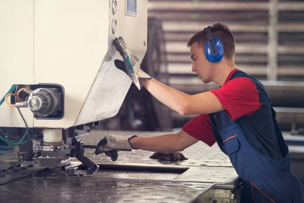 Inside a factory, industrial worker in action on metal press machine ...