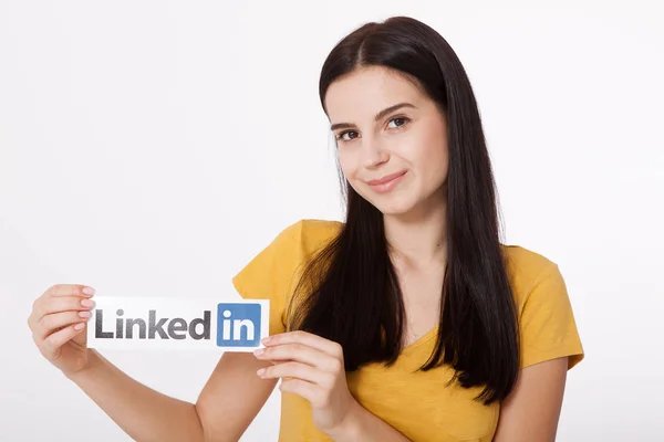 Hand holds Linkedin logo sign printed on paper on white background ...