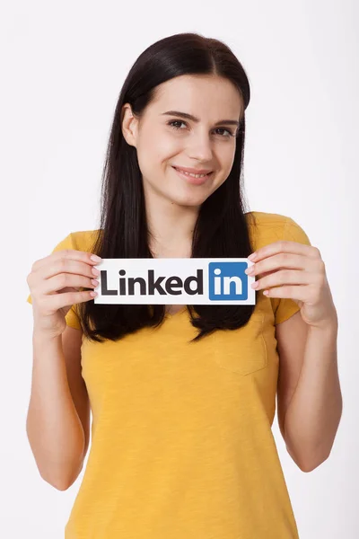 Hand holds Linkedin logo sign printed on paper on white background ...