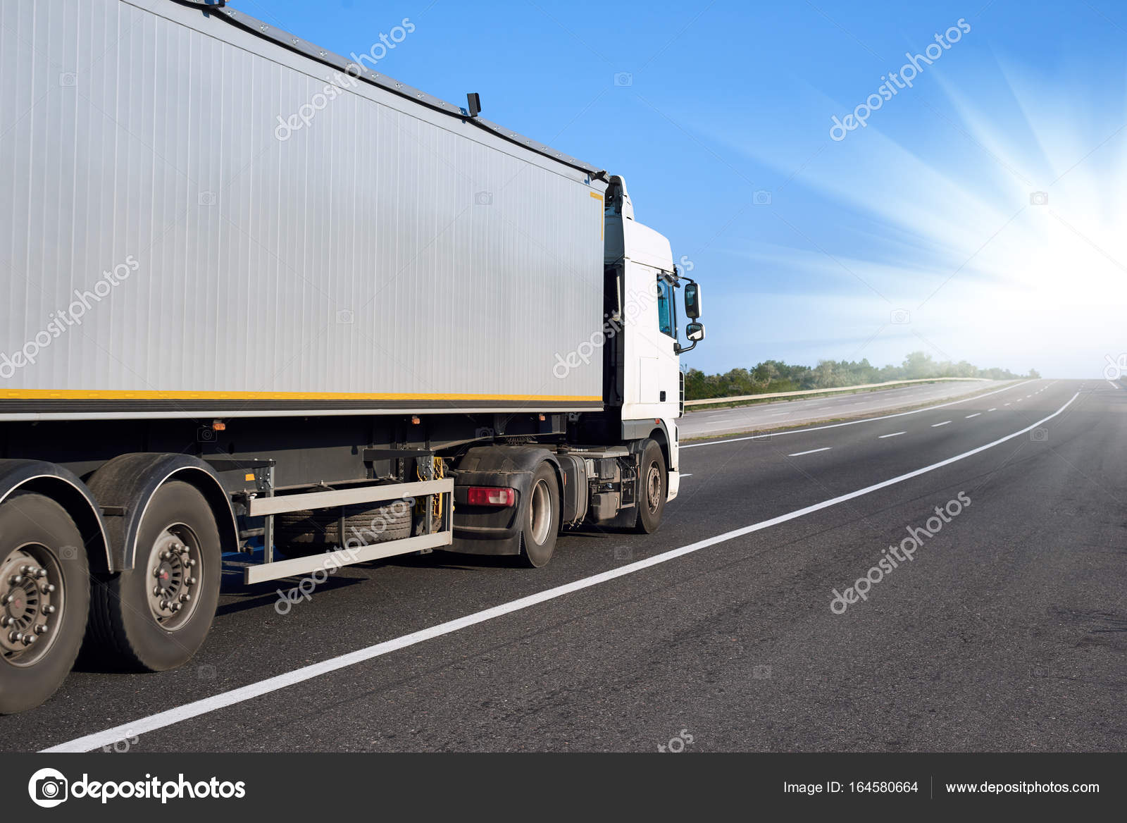 LKW unterwegs mit Container und strahlender Sonne ...