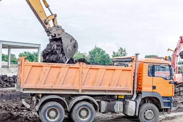 Excavator is loading a truck on building site - Stock Image - Everypixel