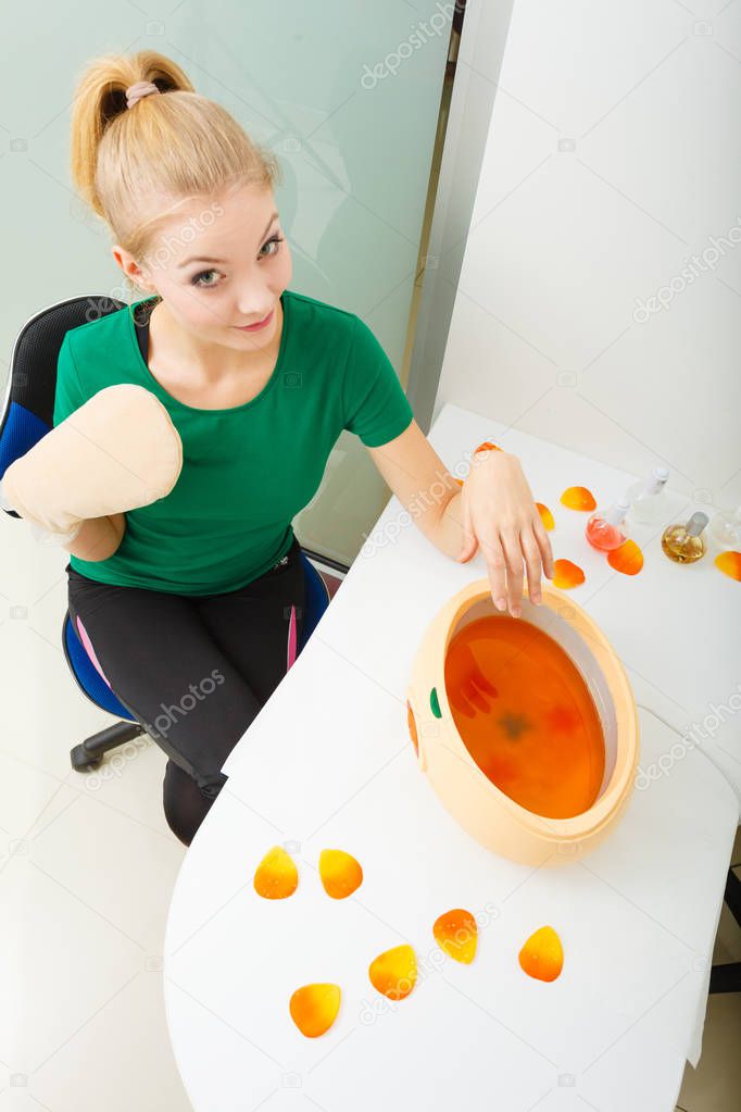 Mujer recibiendo tratamiento de manos de parafina en esteticista 2024