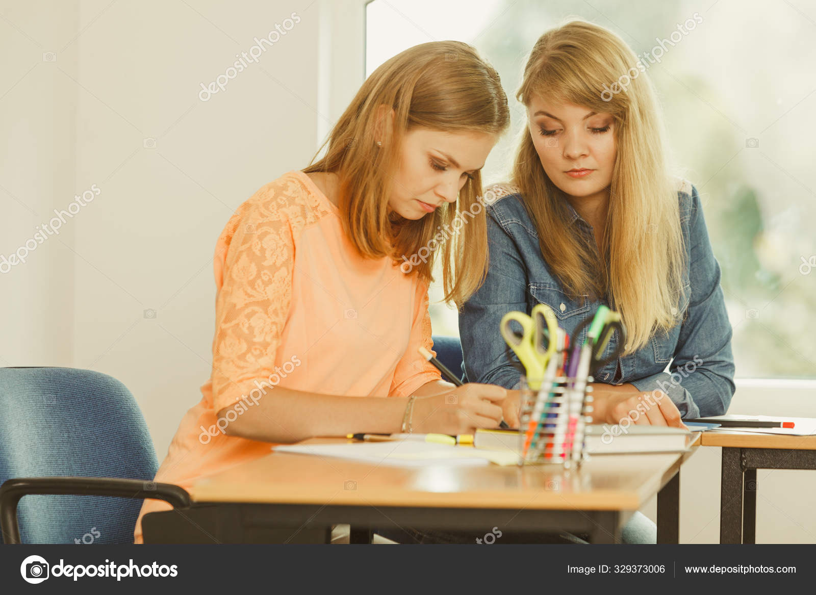 Two students in class Stock Photo by ©Voyagerix 329373006