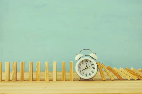A clock stopping the domino effect. retro style image executive and ...