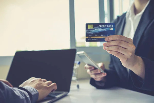 Both business people use laptop and phones to register online purchases ...