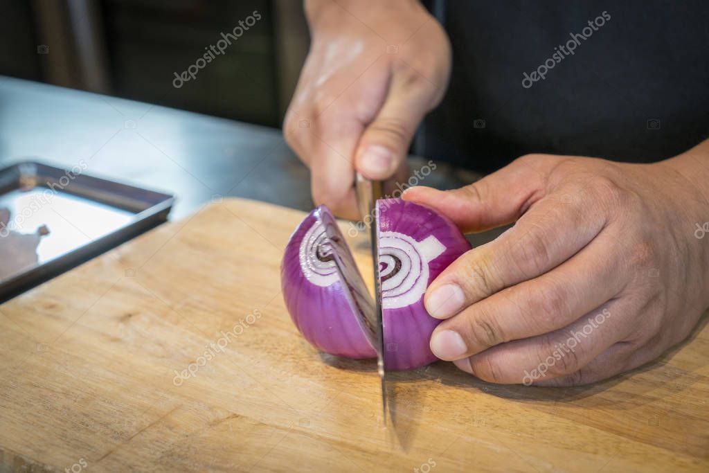 Chef picando una cebolla roja con un cuchillo en la tabla de cortar 2023