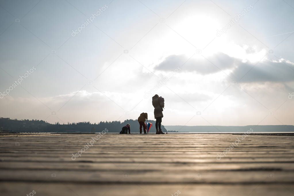 Madre con sus tres hijos de pie en el muelle de madera mirando al ...