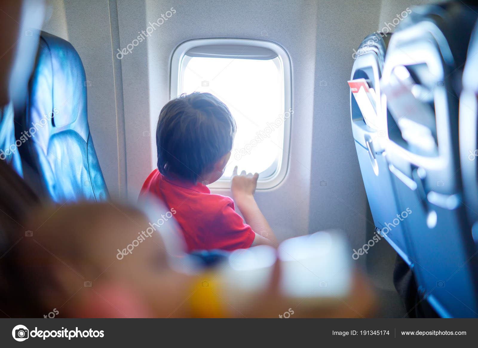 Little kid boy looking outside of plane window during flight on ...