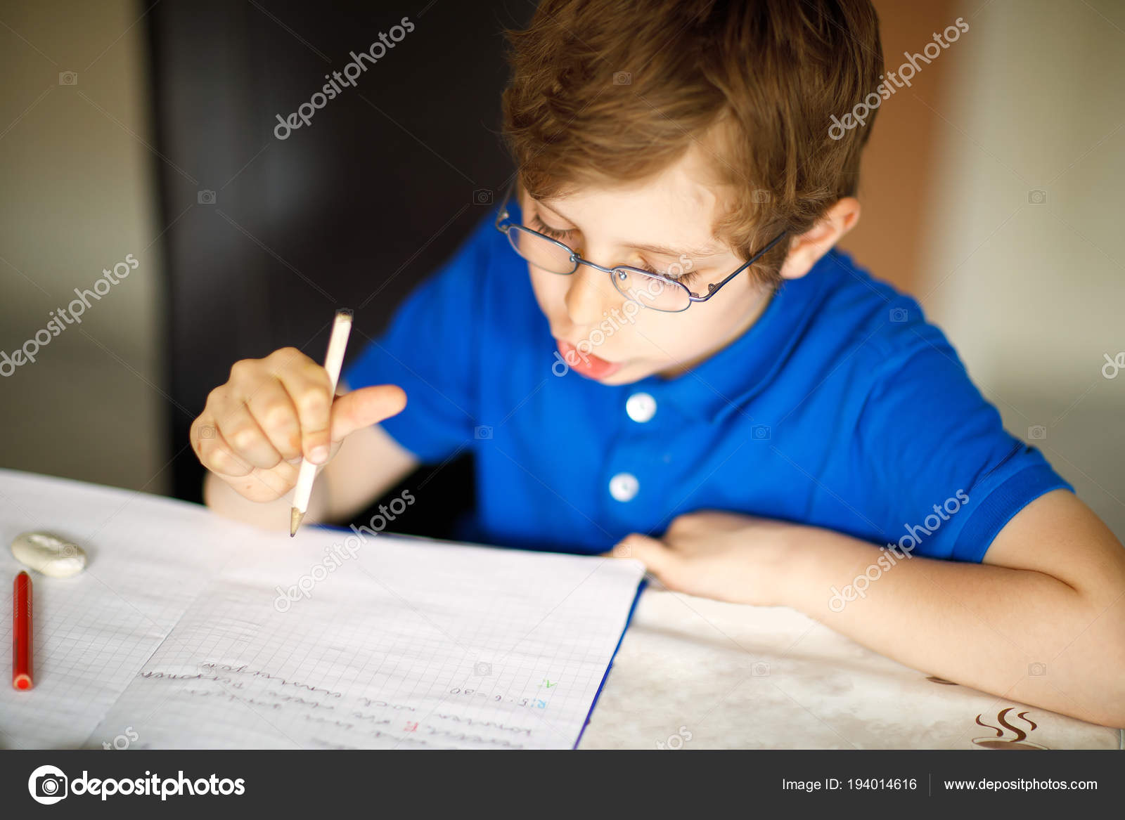 Cute little kid boy with glasses at home making homework, writing ...