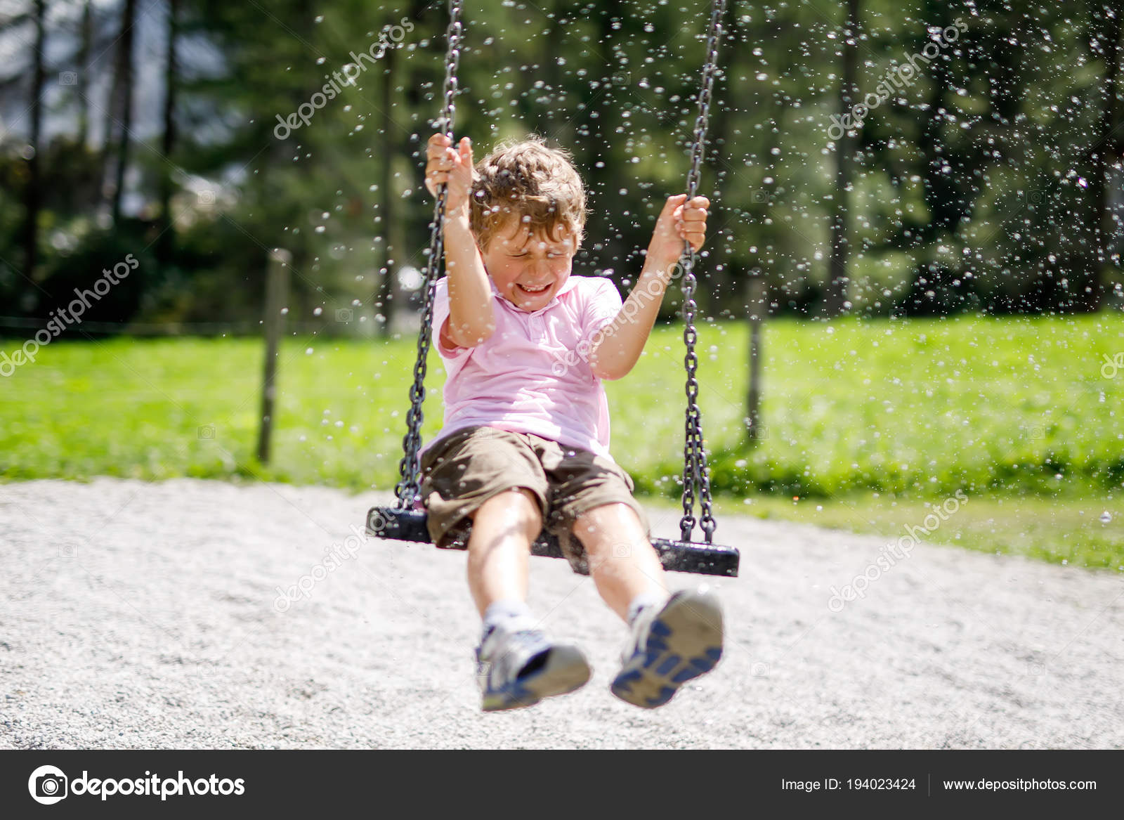 Funny kid boy having fun with chain swing on outdoor playground while ...