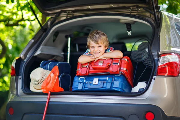 Little kid boy sitting in car trunk just before leaving for vaca Stock ...