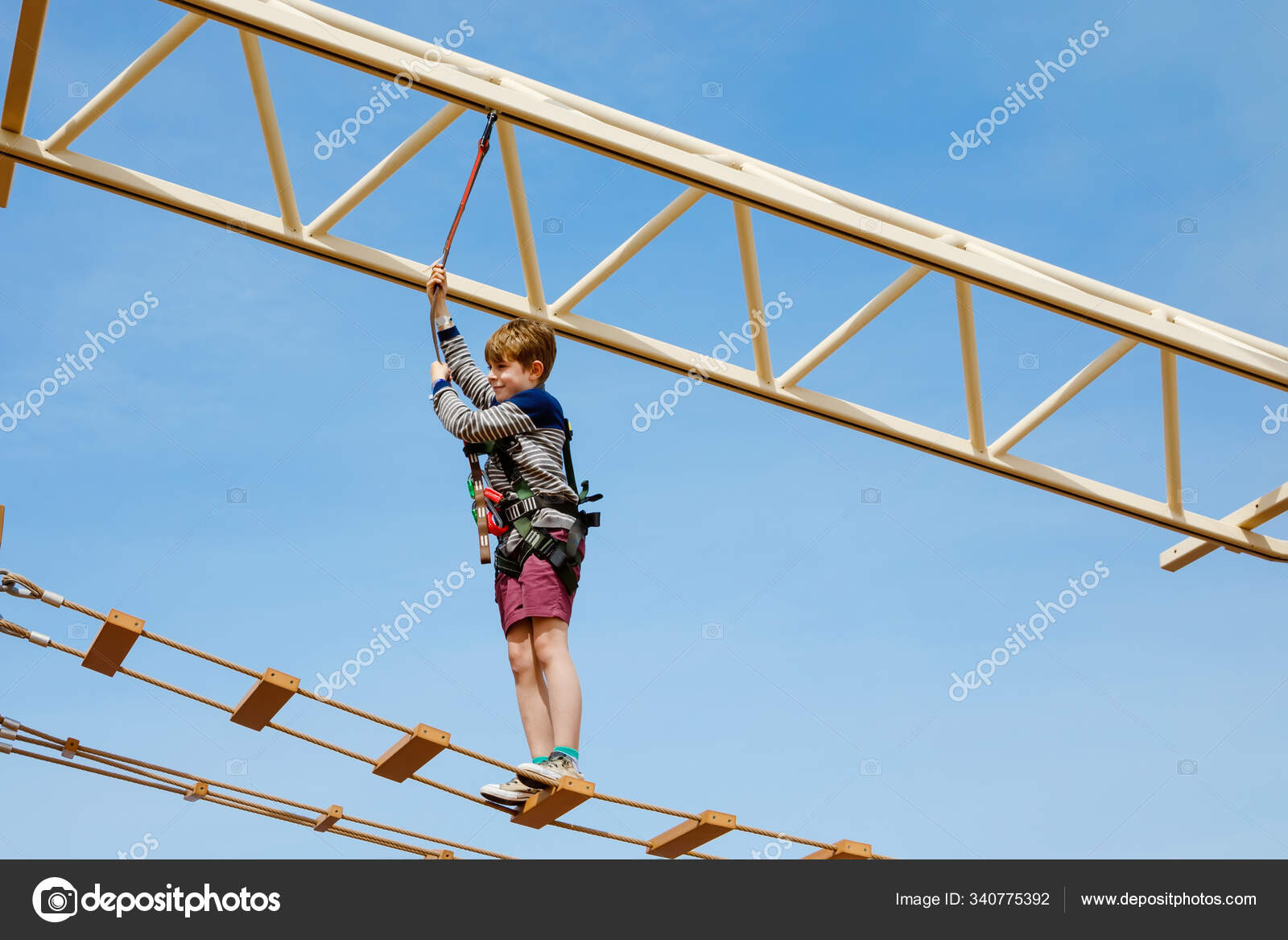 Happy little kid boy climbing on high rope course trail. Active child ...