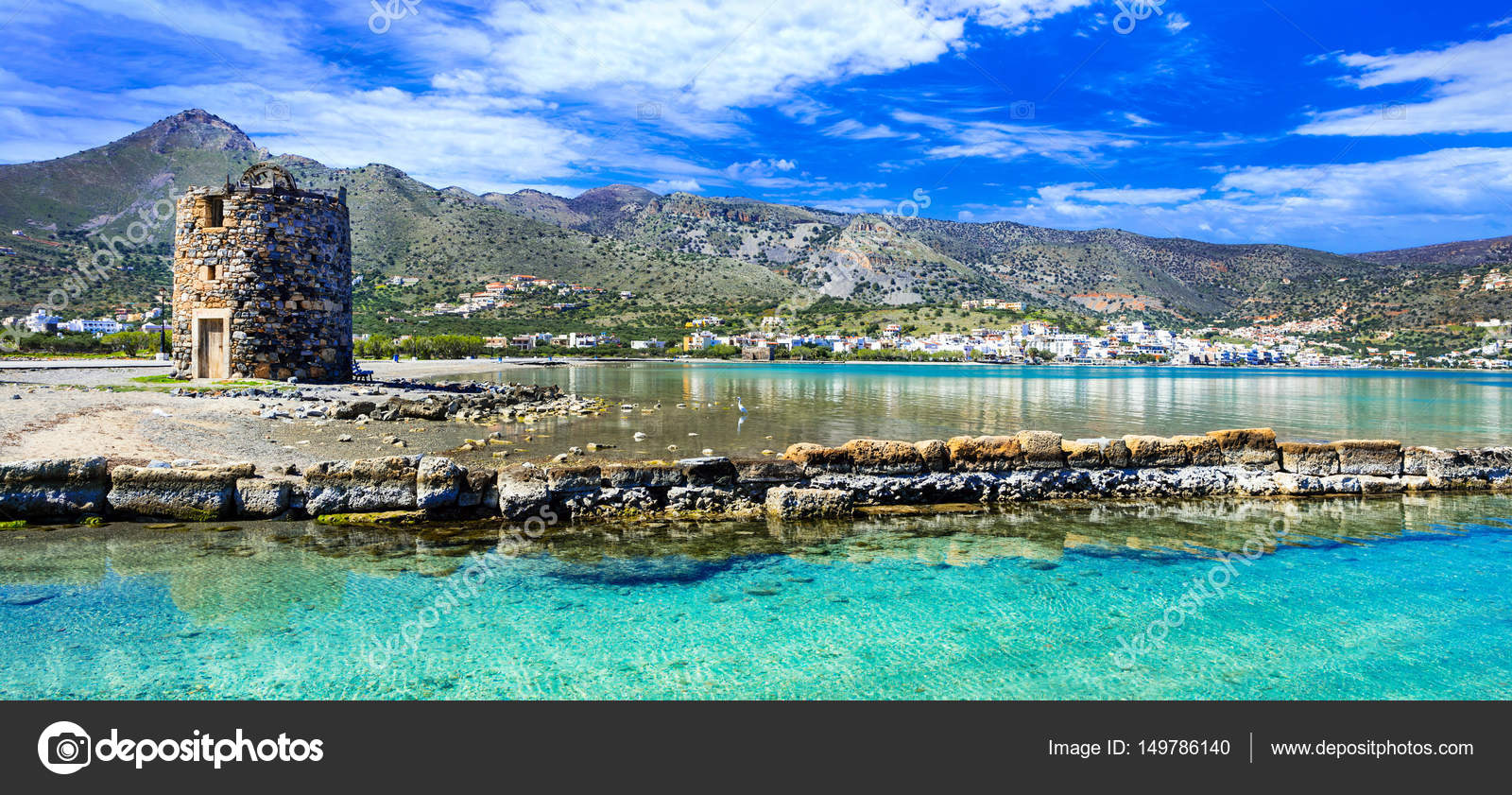 Pictorial scenery with old windmill and crystal waters in Elounda ...