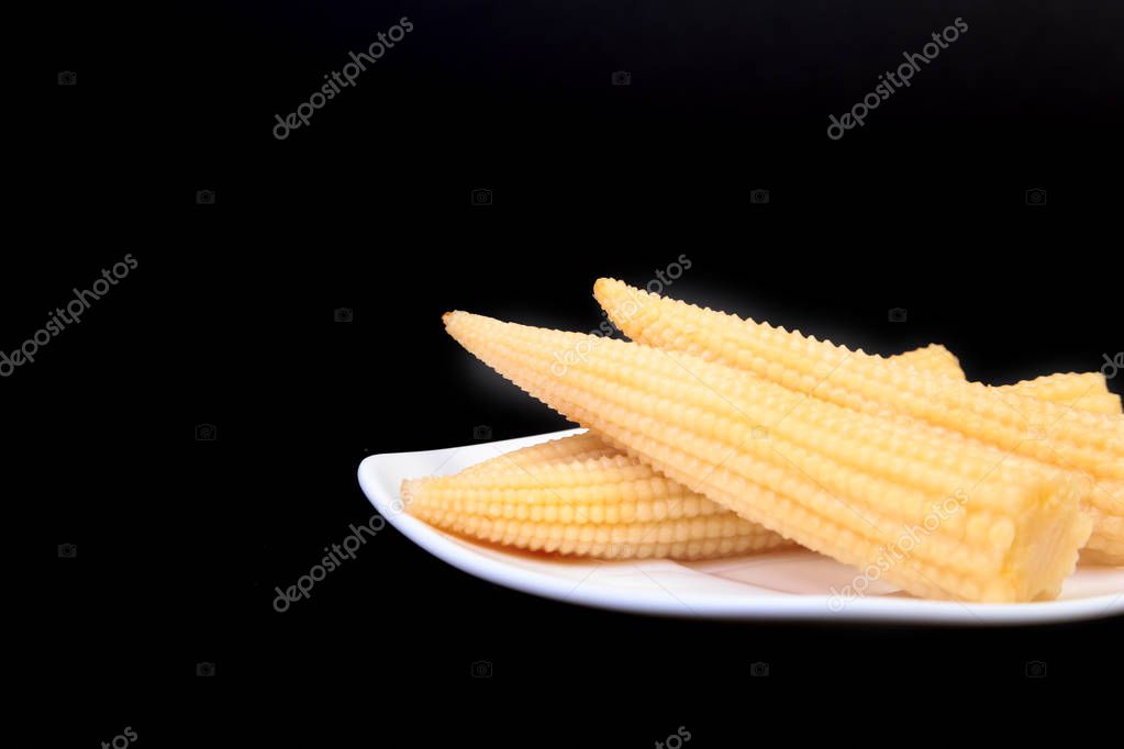 Mini mazorca de maíz conservada en placa sobre tabla de madera. 2023