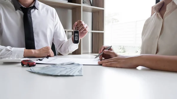 Car sales representative gives the key to customer after signed the ...