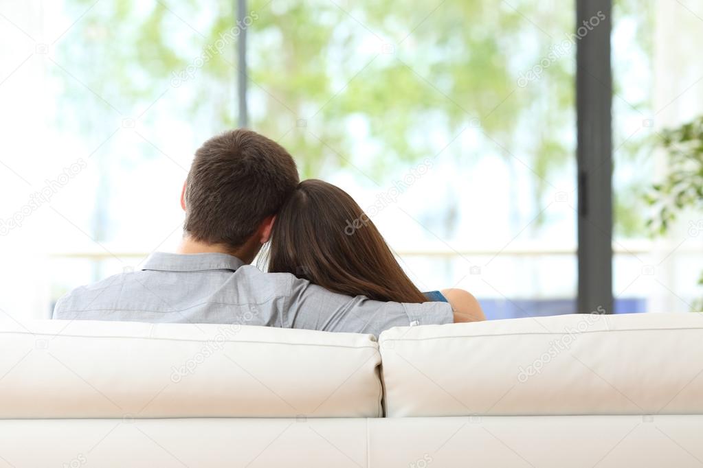 Couple sitting on a couch looking through window — Stock Photo ...