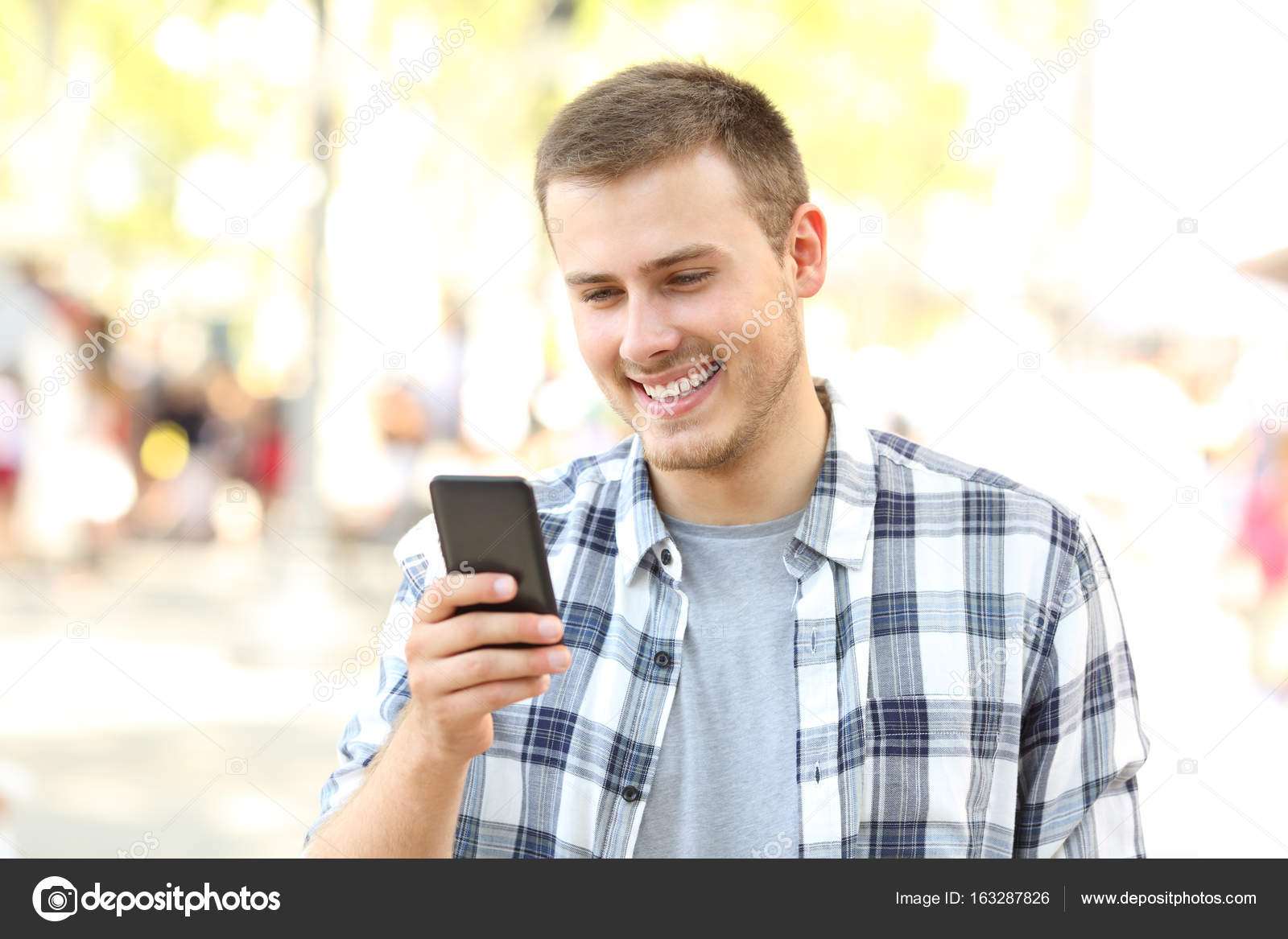 Boy reading messages on the phone on the street Stock Photo by ...