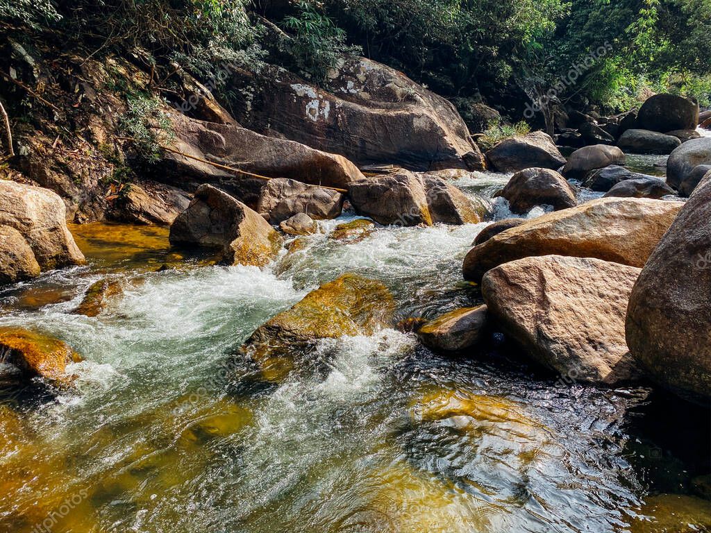Un pequeño río de montaña fluye entre grandes piedras en áreas ...
