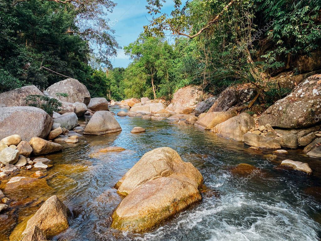 Un pequeño río de montaña fluye entre grandes piedras en áreas ...