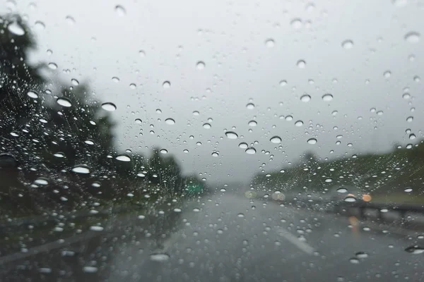 Rain drop falling on car windshield, drive car on street in city in ...