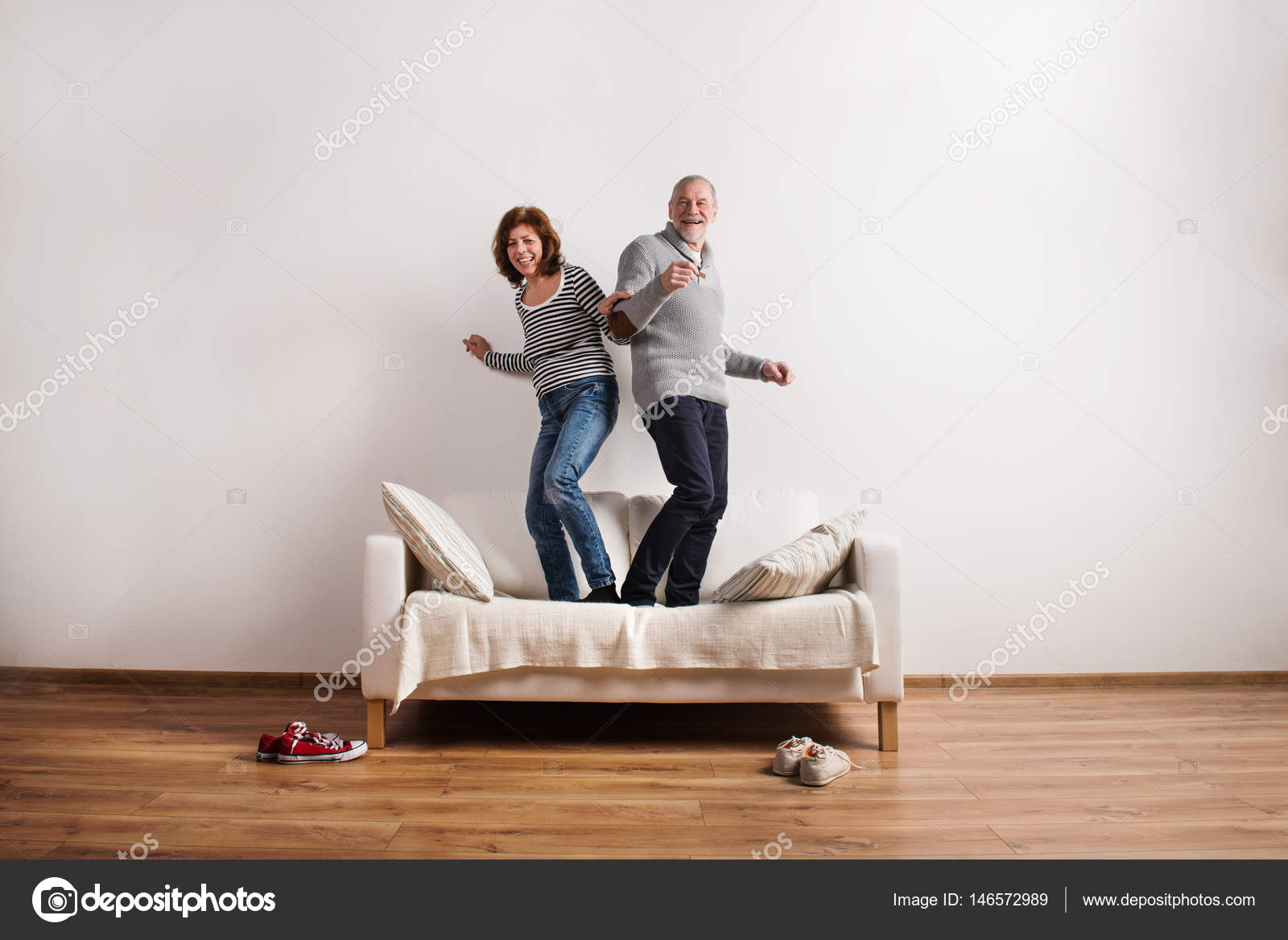 Beautiful senior couple standing on couch, dancing. Studio shot ...