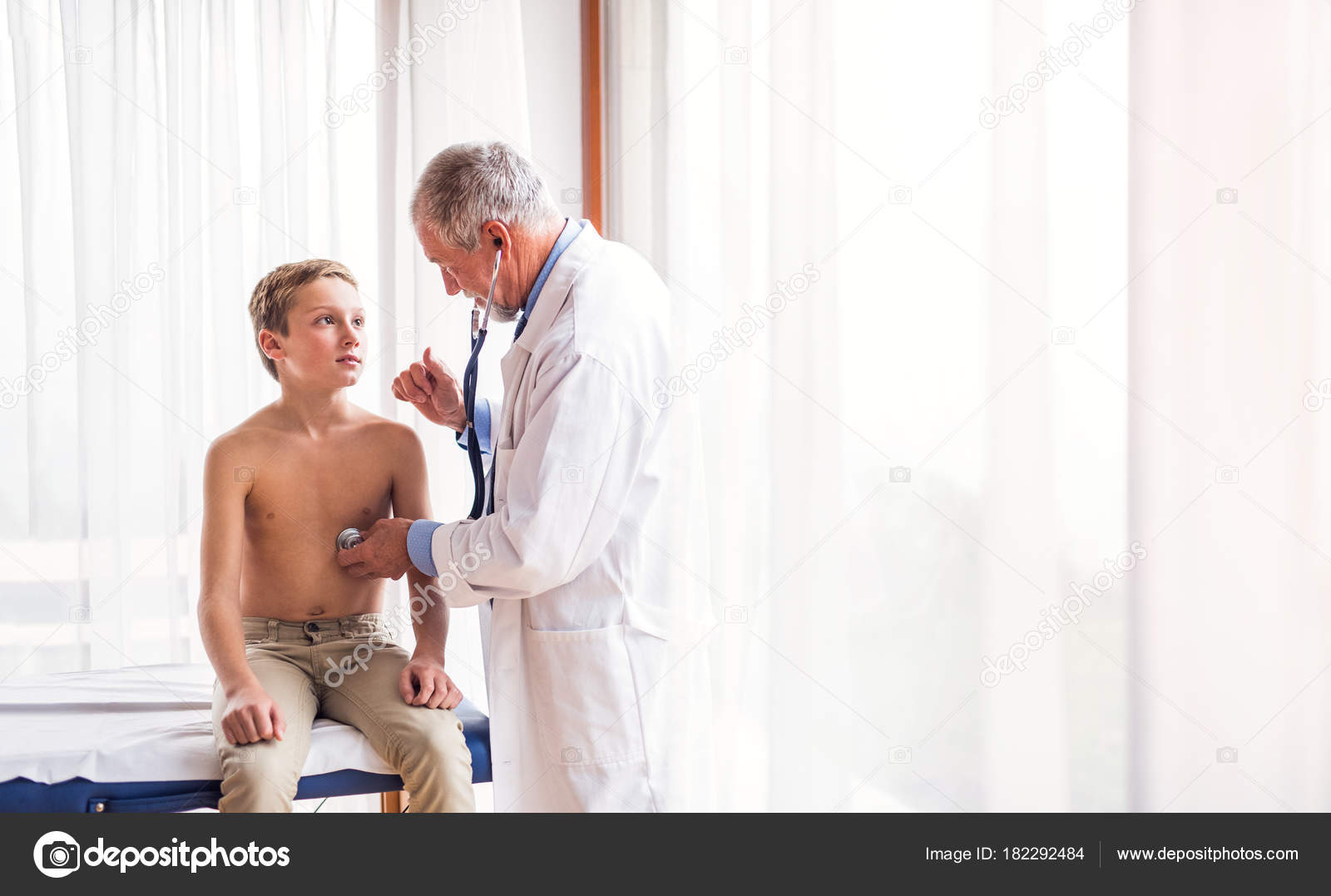Senior doctor examining a small boy in his office. — Stock Photo ...