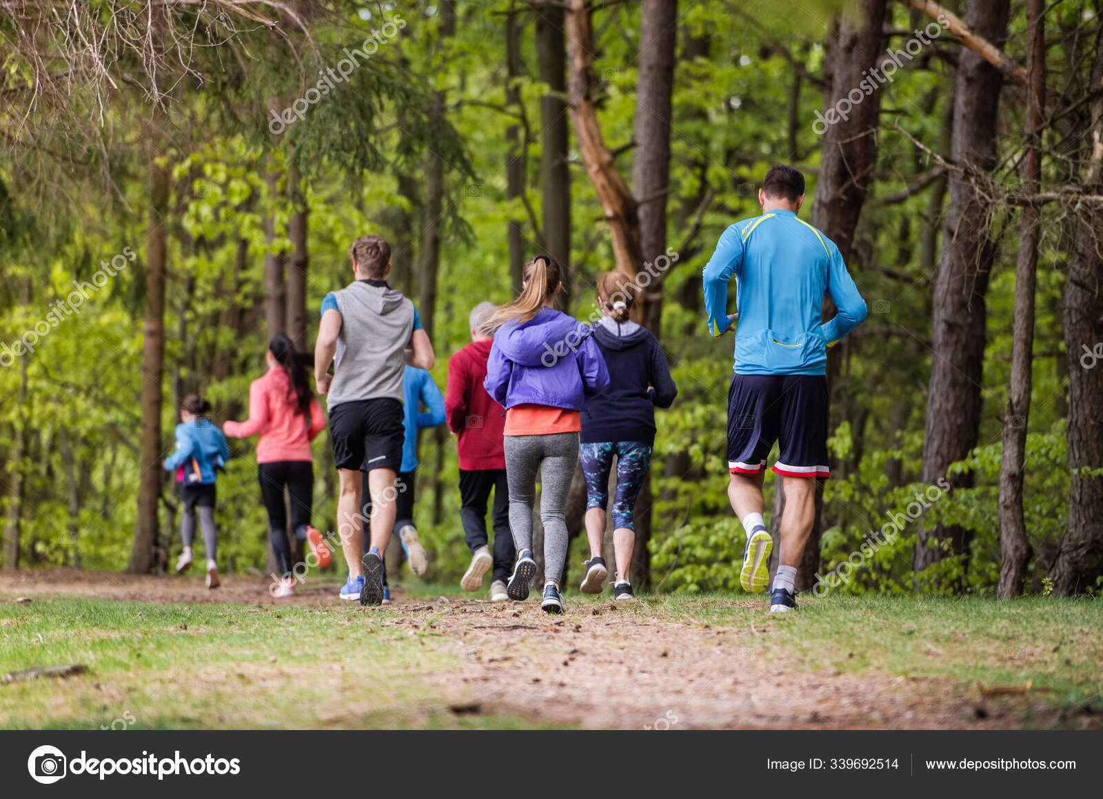 Rear view of large group of multi generation people running in nature ...