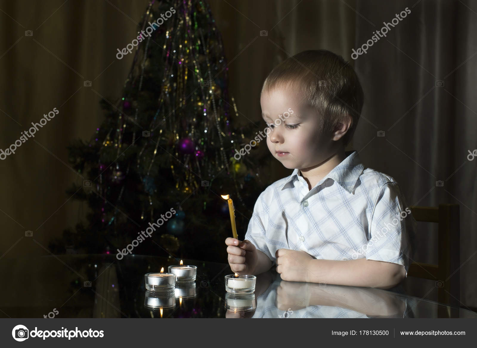 Little boy lights candles on a background of New Year's fir Stock Photo ...
