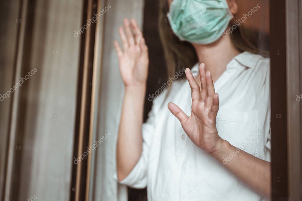 La mujer que usa protección antifaz en la ventana espera a que la ...
